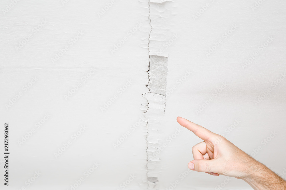 Man's hand finger pointing to the cracked ceiling in a house. Building ...