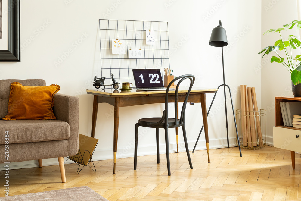 Real photo of a simple desk with a laptop, chair, wall organizer next a ...