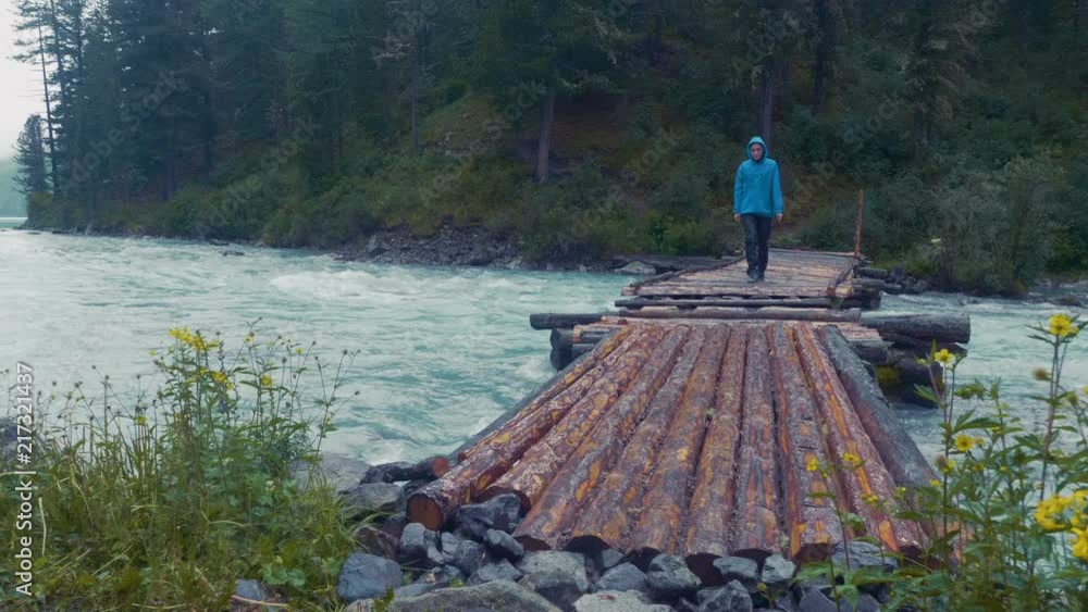 Model released man hiking on log foot bridge over river into through ...