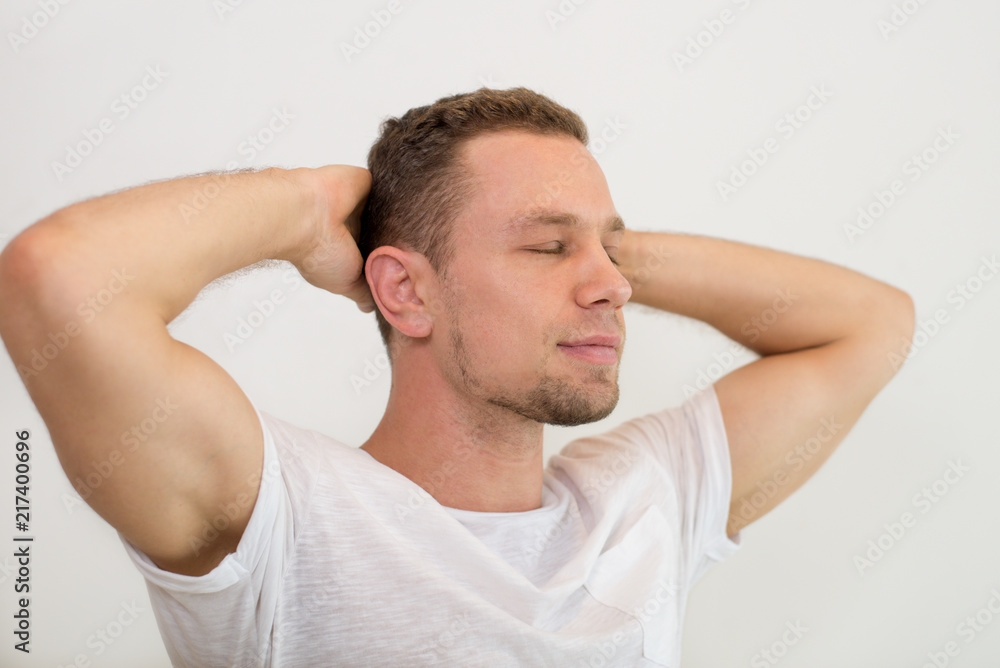 Relaxed handsome man keeping hands behind head. Young guy having rest ...