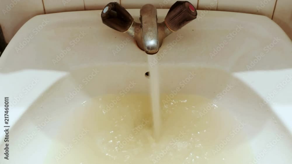 Wash basin full of dirty water / Dirty water flows from the tap into ...
