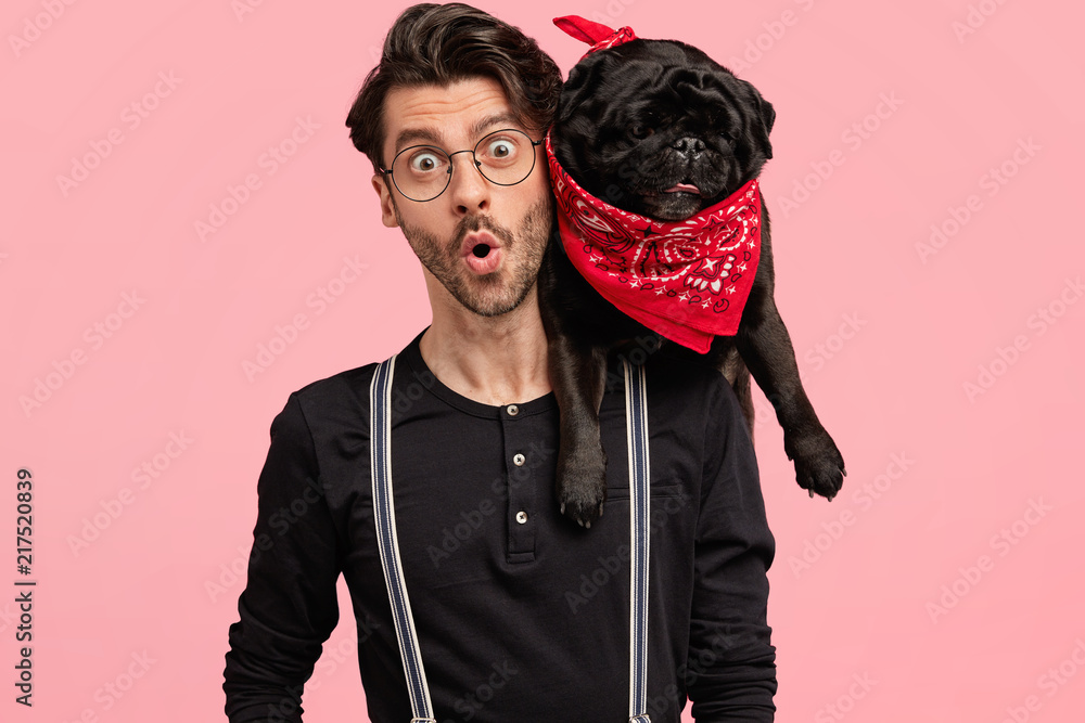 Shocked handsome male owner of dog, looks with terrible expression ...