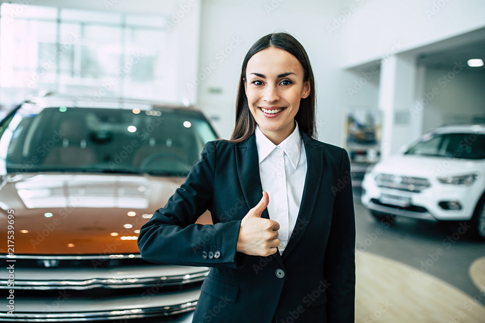 Portrait of beautiful young saleswoman in black suit standing inside ...