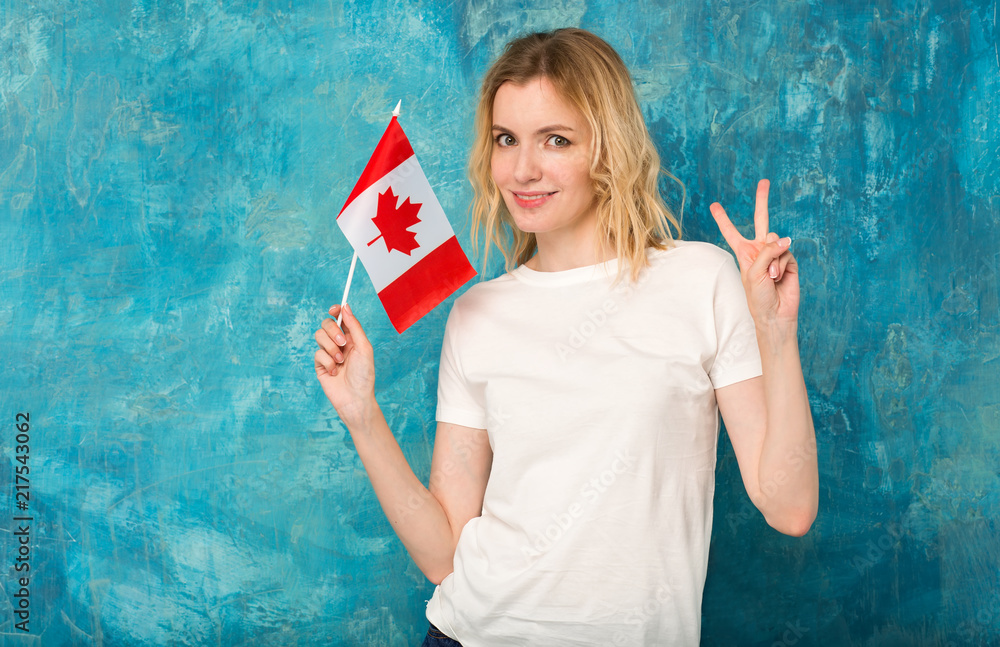 Beautiful blond woman with the flag of Canada on a blue background. She ...