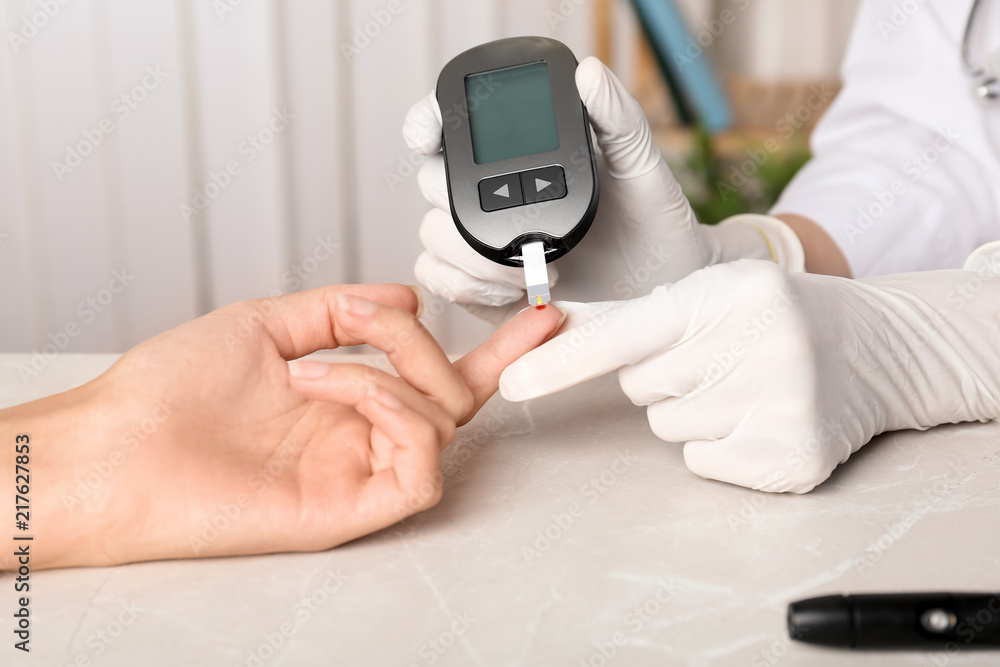 Doctor checking blood sugar level with glucometer at table. Diabetes ...