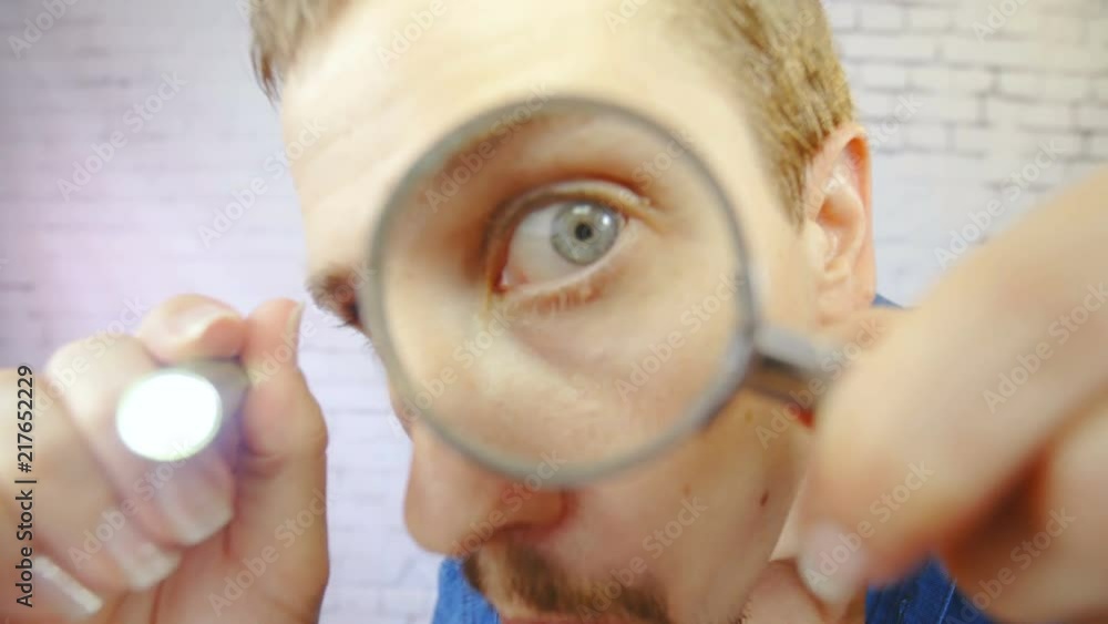 Man with magnifying glass and flashlight look into camera lens 4K ...