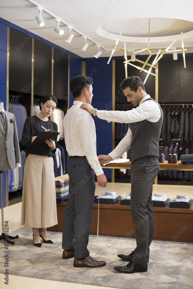 Fashion designers taking measurement of customer Stock Photo | Adobe Stock