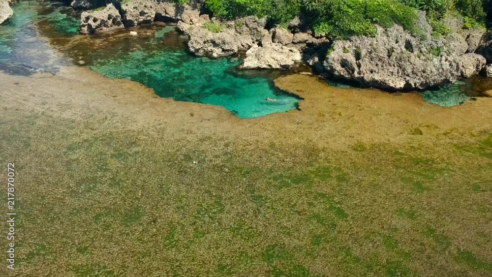 Droneshot of the magpupunko tidal pools. Girl diving into one of the ...
