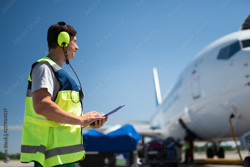 Checking the jet. Side view of airport crew member. Man wearing ...
