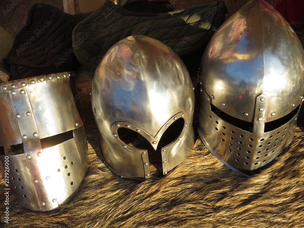 Metal knightly helmets on a bearskin rug. Armor of middle ages ...