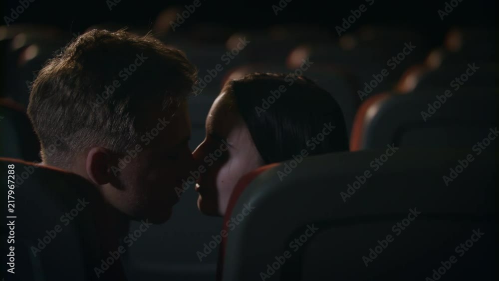Love couple alone at empty cinema hall. Young guy and girl kissing in ...