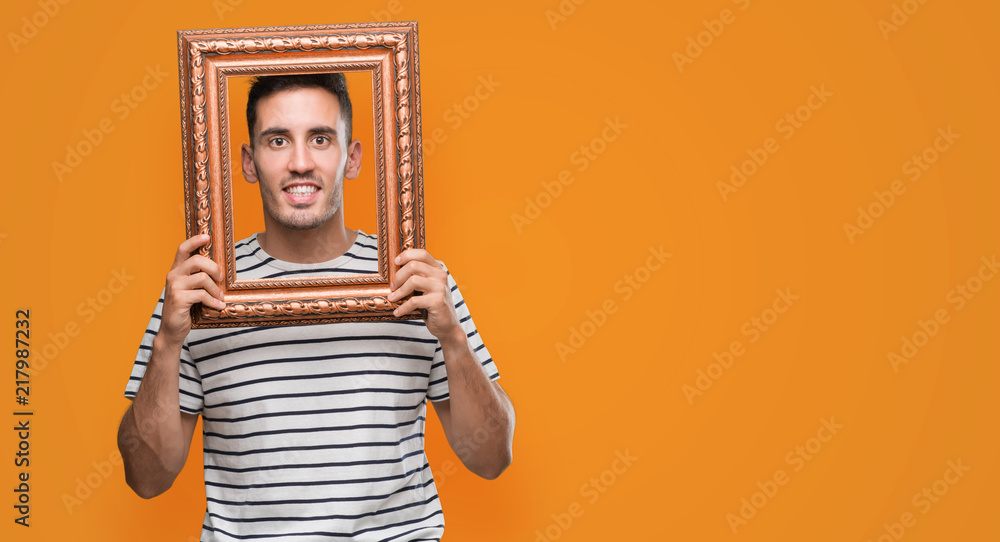 Handsome young man looking through vintage art frame with a happy face ...
