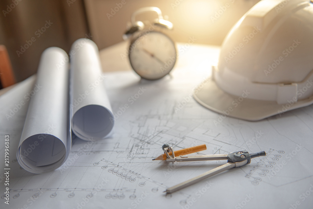 Clock, helmet and compass tool on architectural drawing plan of house ...