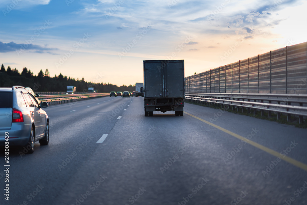 Highway traffic in sunset. road with metal safety barrier or rail ...
