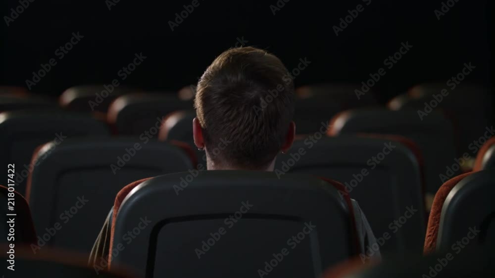 Vidéo Stock Stylish guy sitting in empty movie theater alone. Back view ...