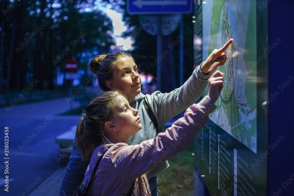 Two girls teenager are looking for the way route on the map scheme at ...