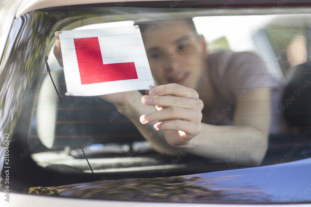 Learner driver placing letter L on rear window of car Stock Photo ...