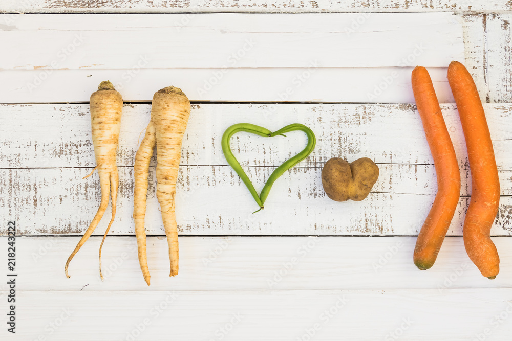Love concept. Two human shaped parsley roots, carots, spring-bean and ...