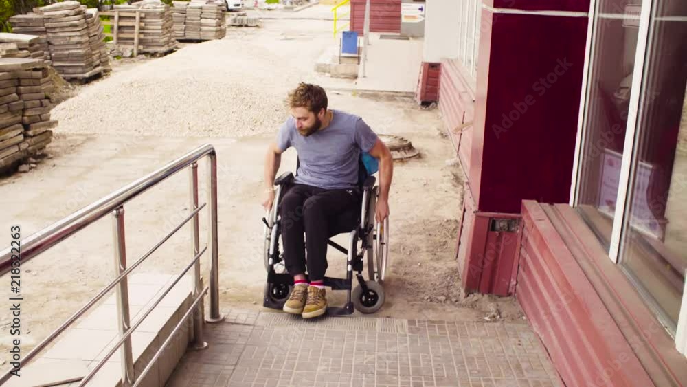 Vidéo Stock A disabled man in a wheelchair rises up the inclined plane ...