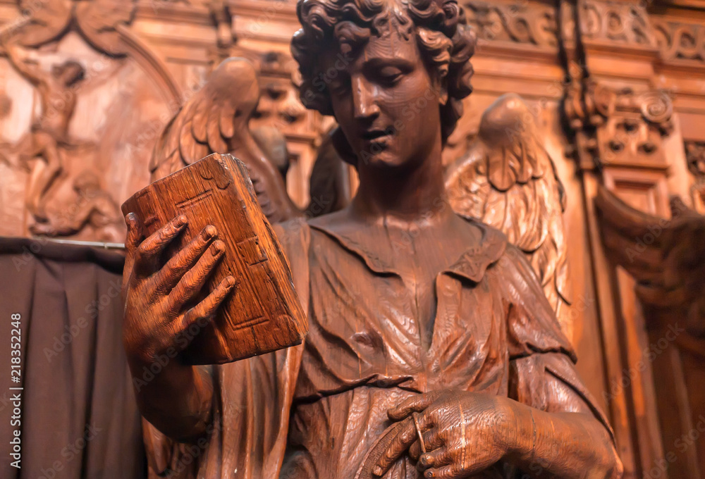 Reading angel holding an old book, wooden statue in 17th century ...