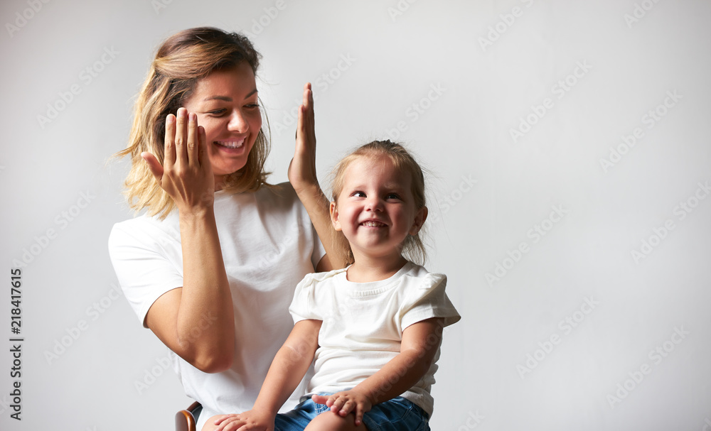 Little girl playing peekaboo game with her mother on white background ...