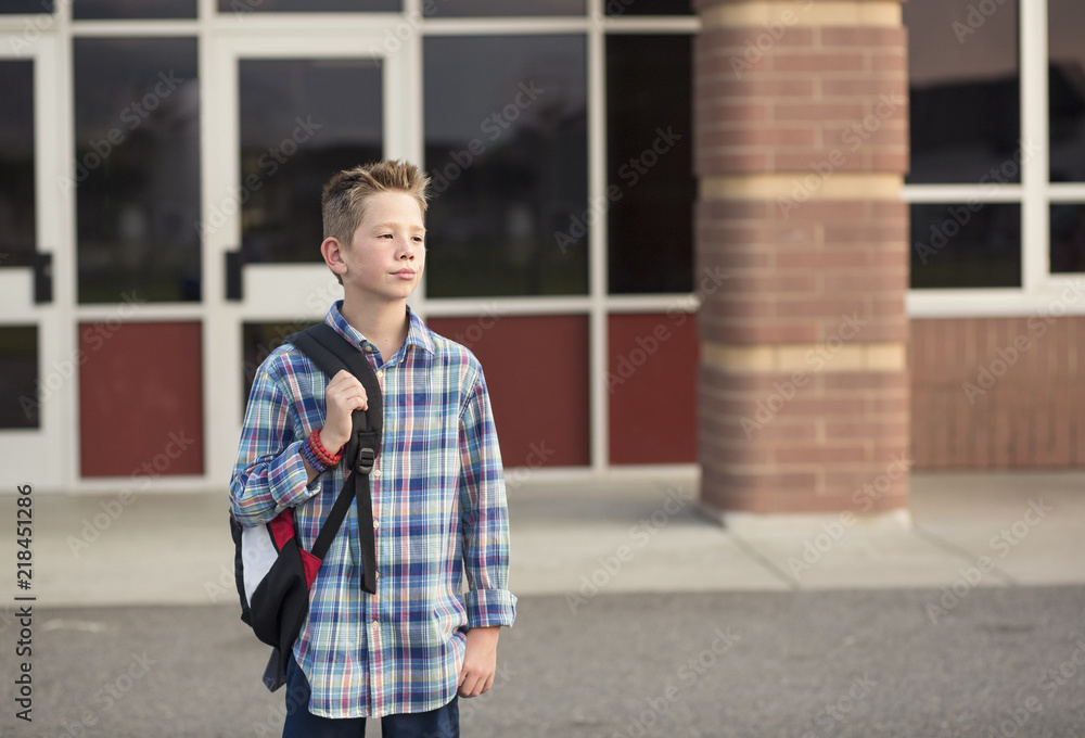 Candid portrait of a male elementary school student standing outside ...