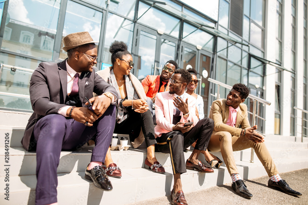 relaxing joyful friends talking while sitting on stairs in front of the ...