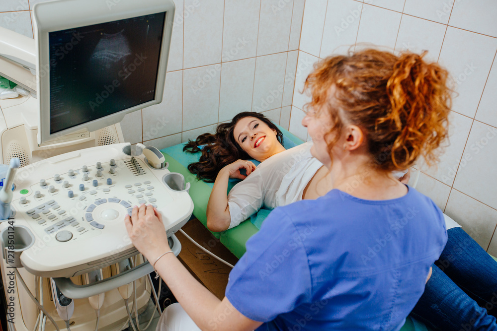 Ultrasound examination of the fetus. Red haired woman gynecologist ...