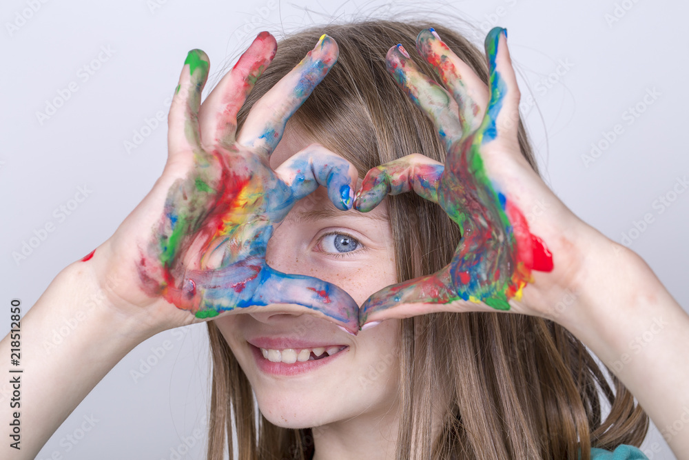 Portrait young girl and child hands painted make a heart shape ...