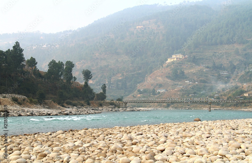 Rocky riverside and bridge across River Puna Tsang Chu in Khuruthang ...