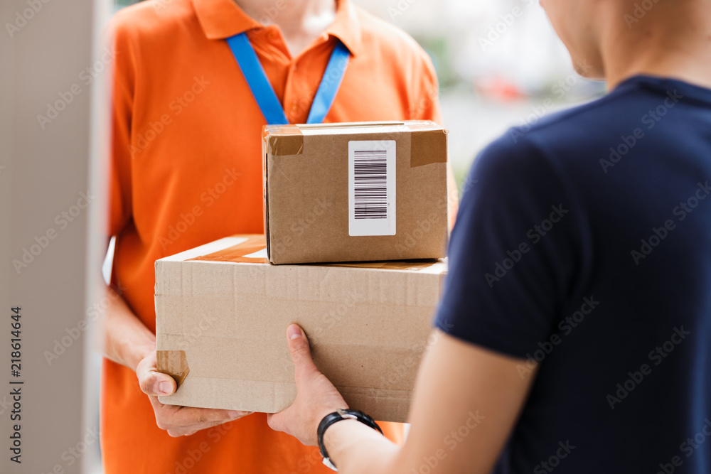 A person wearing an orange T-shirt and a name tag is delivering parcels ...