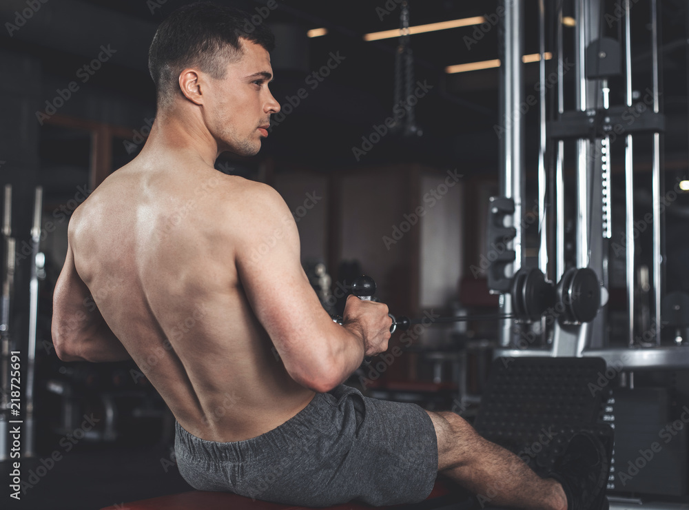 Shredded shirtless guy is using horizontal row machine indoors. He is ...