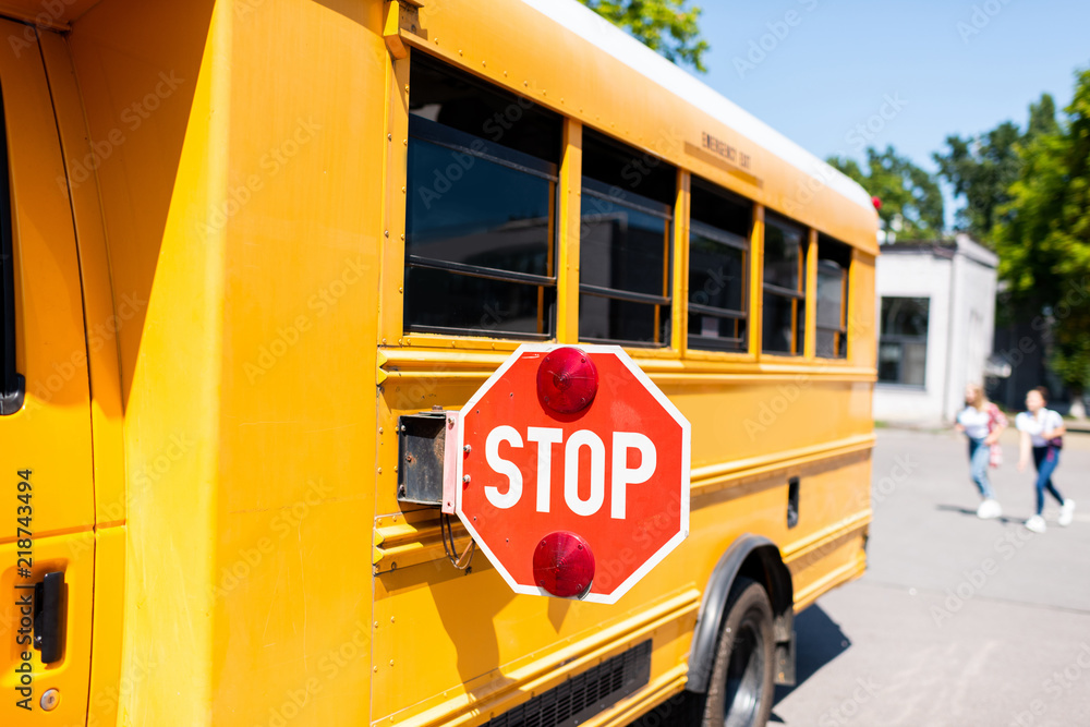 partial view of school bus with stop sign standing on parking with ...