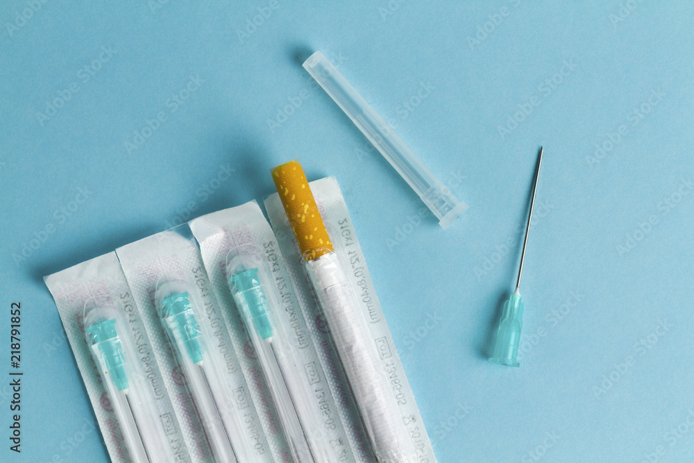 Cigarettes and needles for injections on a blue background. The concept ...