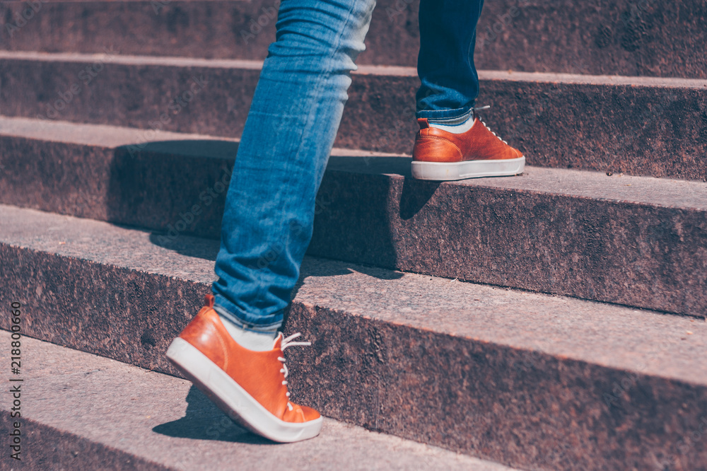A girl in jeans and beautiful leather shoes steps over the marble steps ...