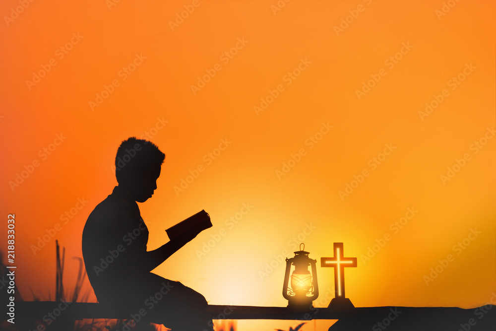 Boy reading bible with oil lamp and sunset background.christian concept ...