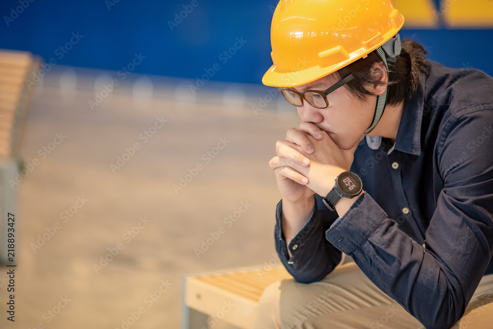 Young Asian engineer or architect man feeling tried and stressed while ...