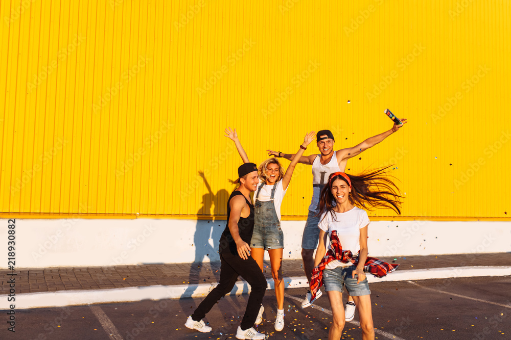 Beautiful cool young jump with confetti on a yellow background, a group ...