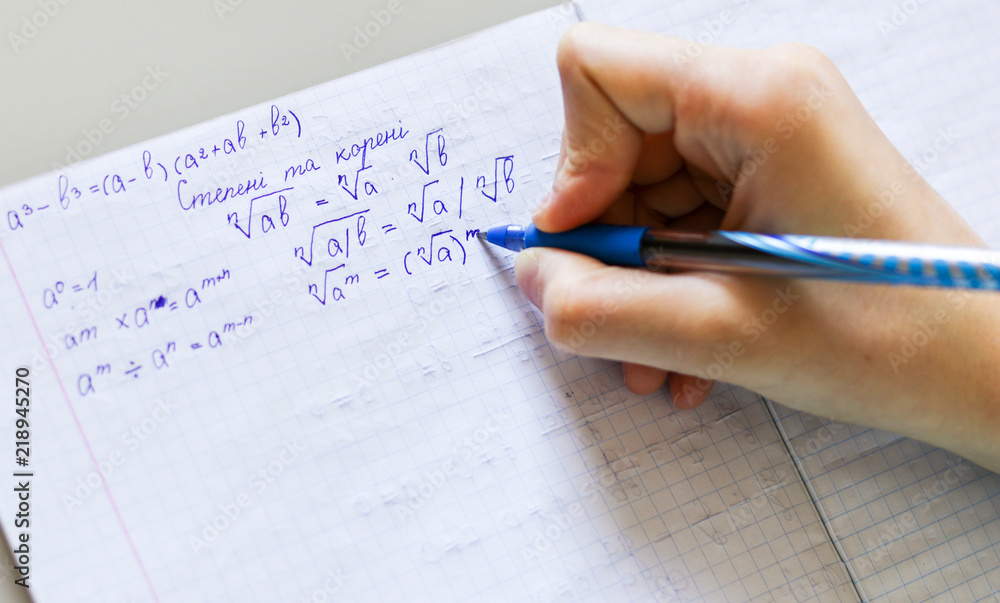 Close-up shot of student hand writing down math formulas of square ...