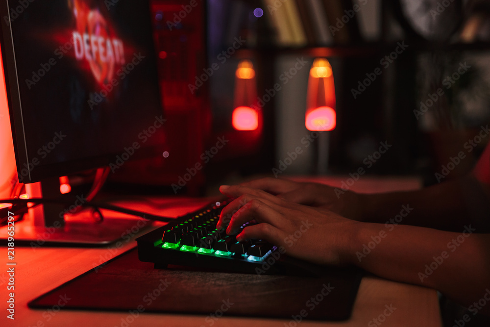 Hands of young gamer man playing video games on computer in dark room ...