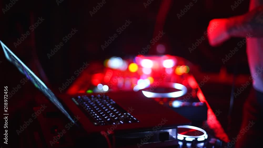 Laptop with mixing program and DJ mixer lights in the dark. Disc jockey ...