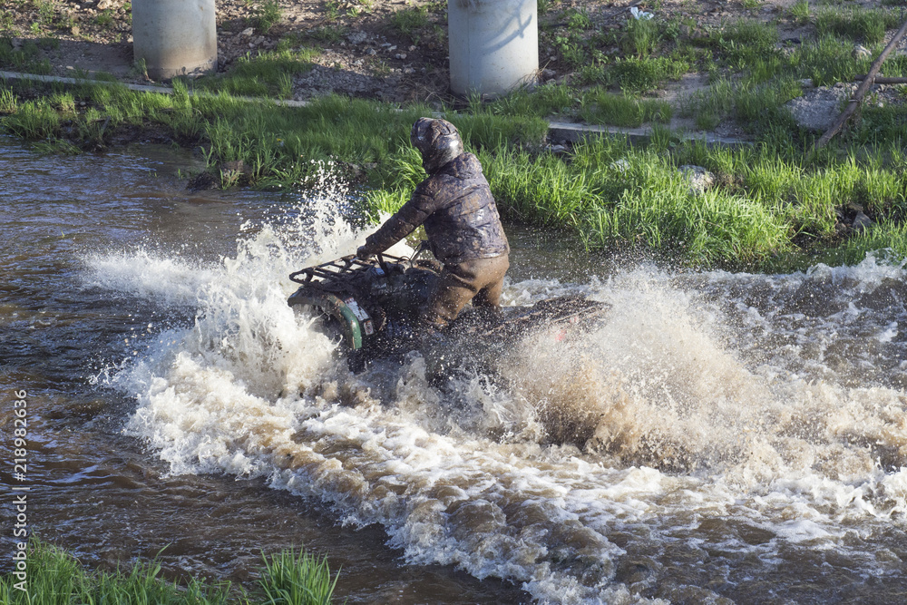 Motorcyclists on an ATV drove into the river. People wash an off-road ...