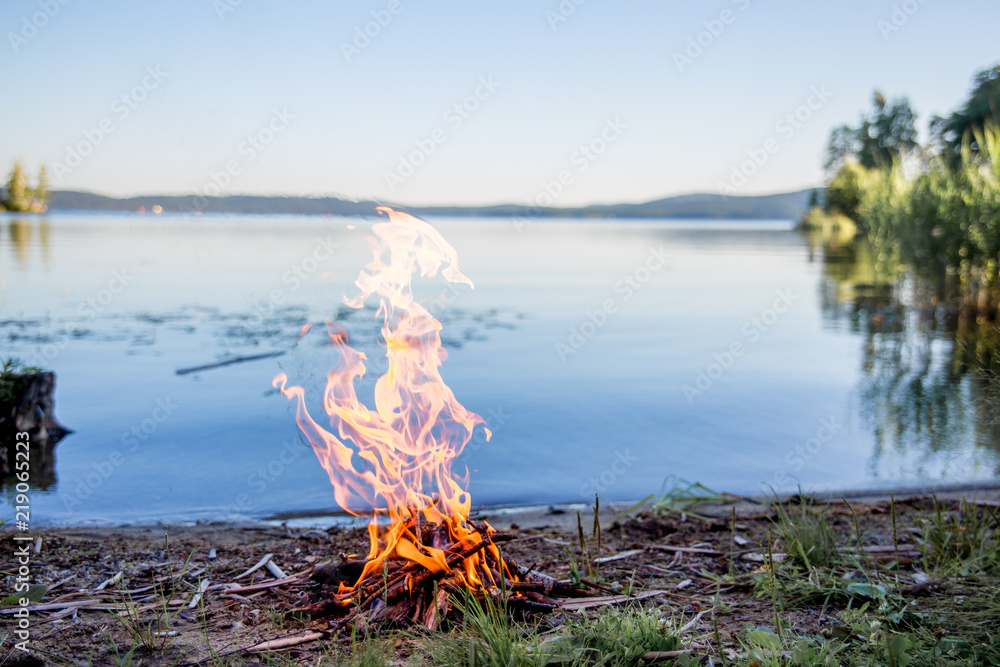 Beautiful campfire in the evening at lake. Fire burning in dusk at ...