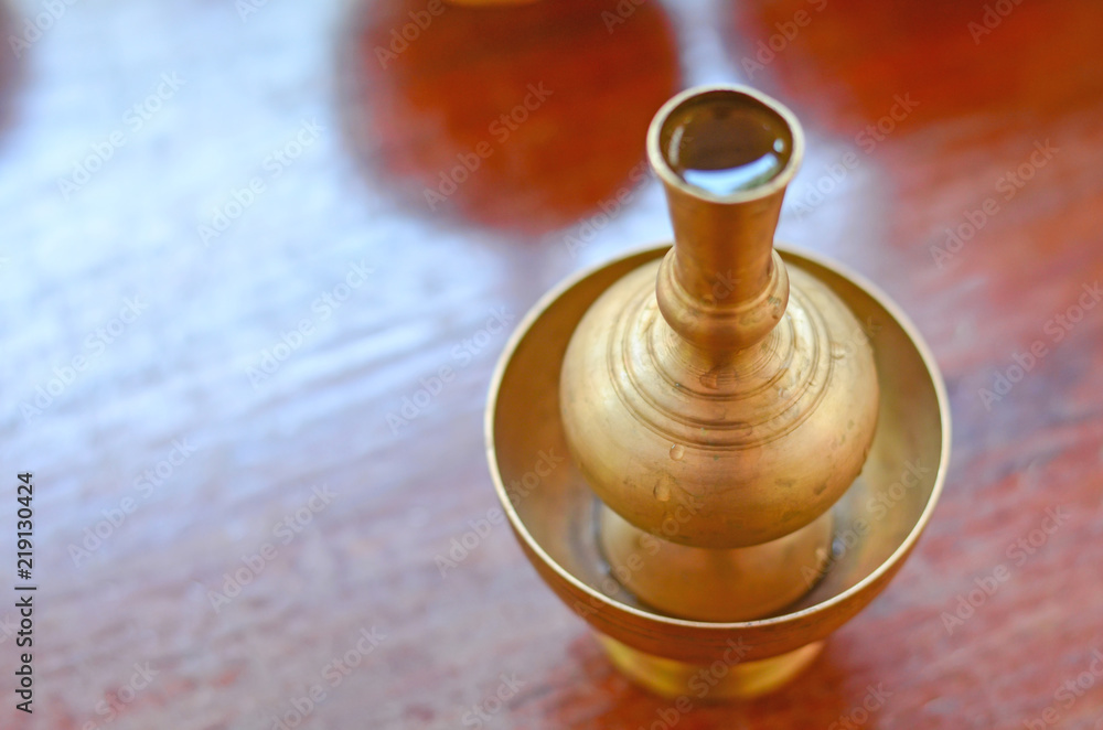 A golden brass pour ceremonial water jar used in traditional Buddhists ...