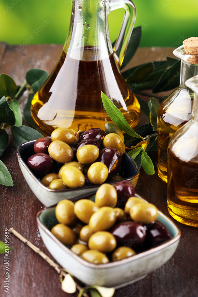Olives. Bottle virgin olive oil and oil in a bowl with some olives ...