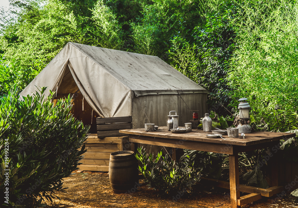 big old tent and campsite in the forest with wooden picnic table ...