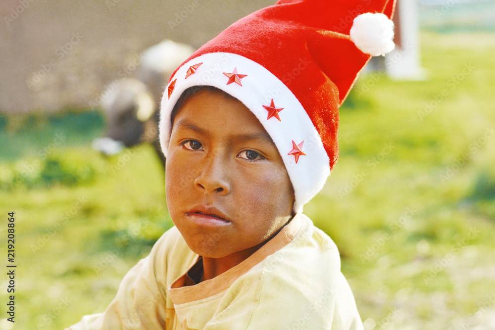 Sad native american boy wearing typical Santa Claus red hat. Stock ...