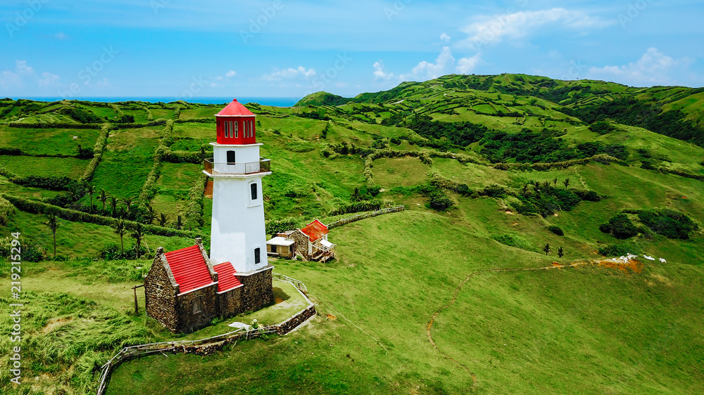 Drone shot of Mahatao Tayid Lighthouse on top rolling hills in the ...