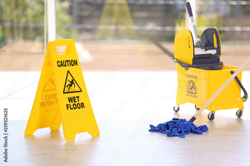 Safety sign with phrase Caution wet floor and mop bucket, indoors ...