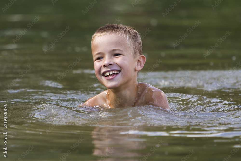 Young smiling child boy swimming in muddy water on sunny summer day ...